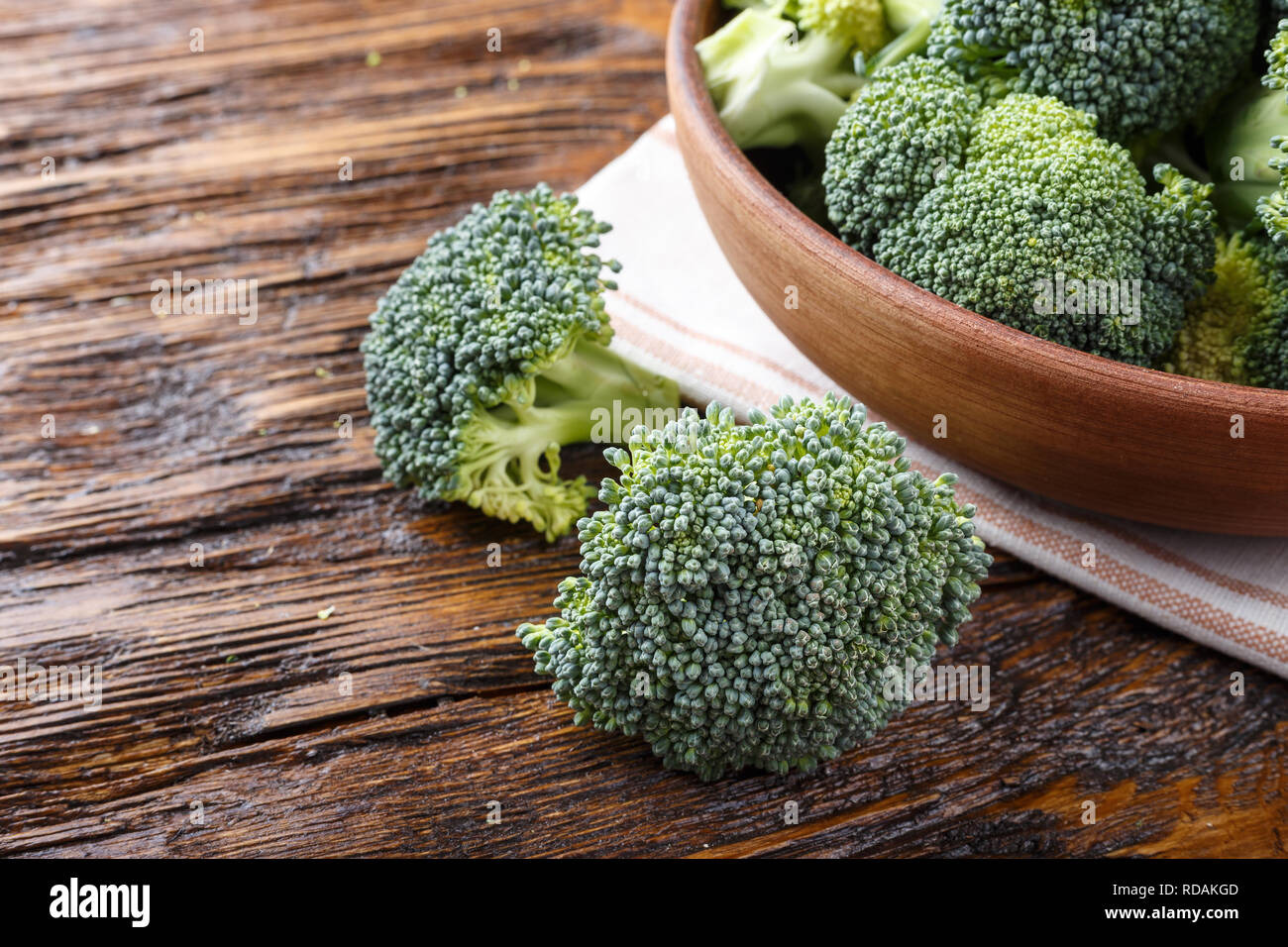 broccoli in a clay plate on a wooden table, next to a whole cabbage are ...