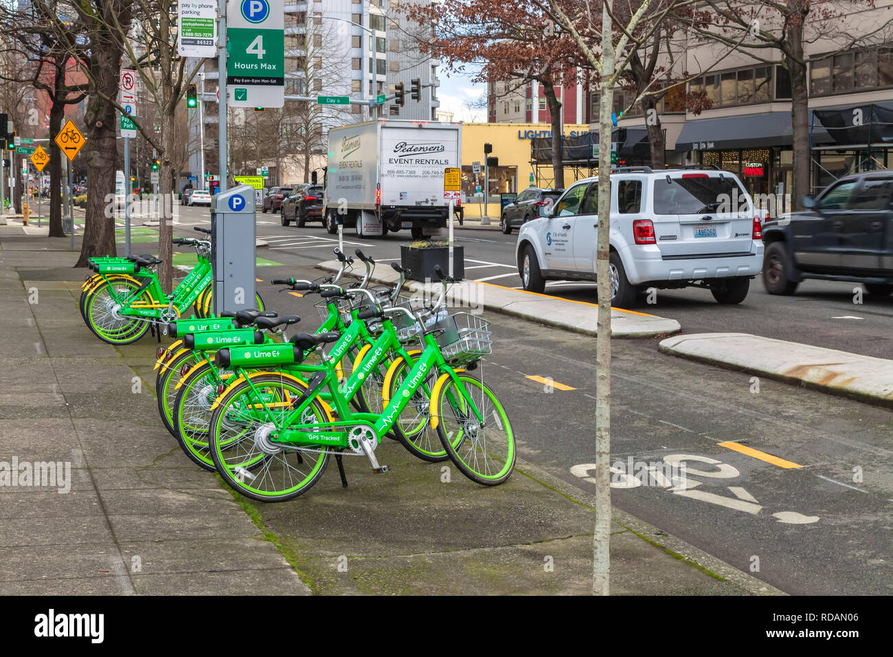 Rental bikes line up on the sidewalk along the street in downtown ...