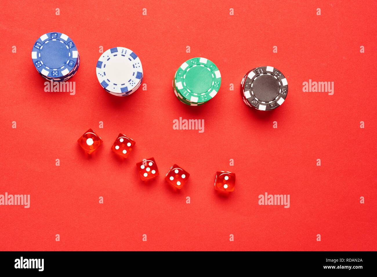 Flat lay concept: image of several red dice and chips on red background ...