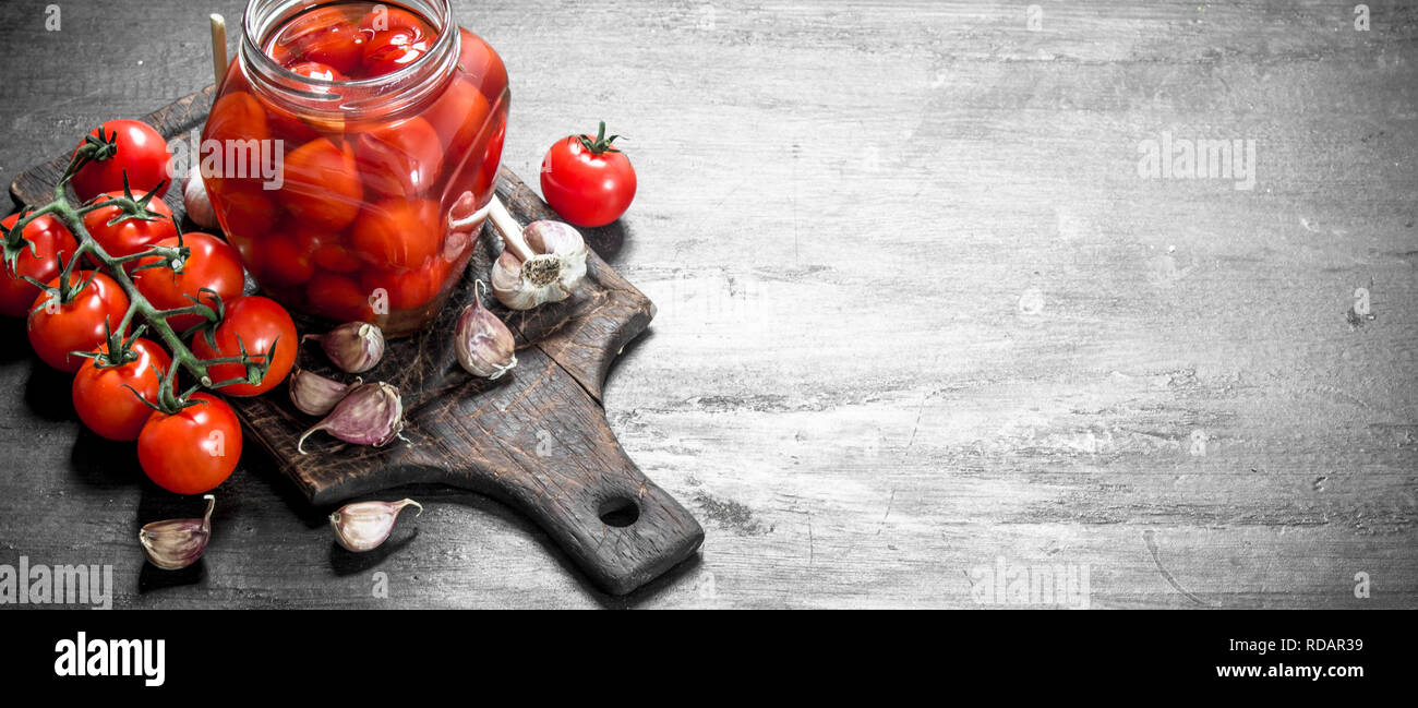 Pickled tomatoes with garlic and herbs. On black background Stock Photo ...