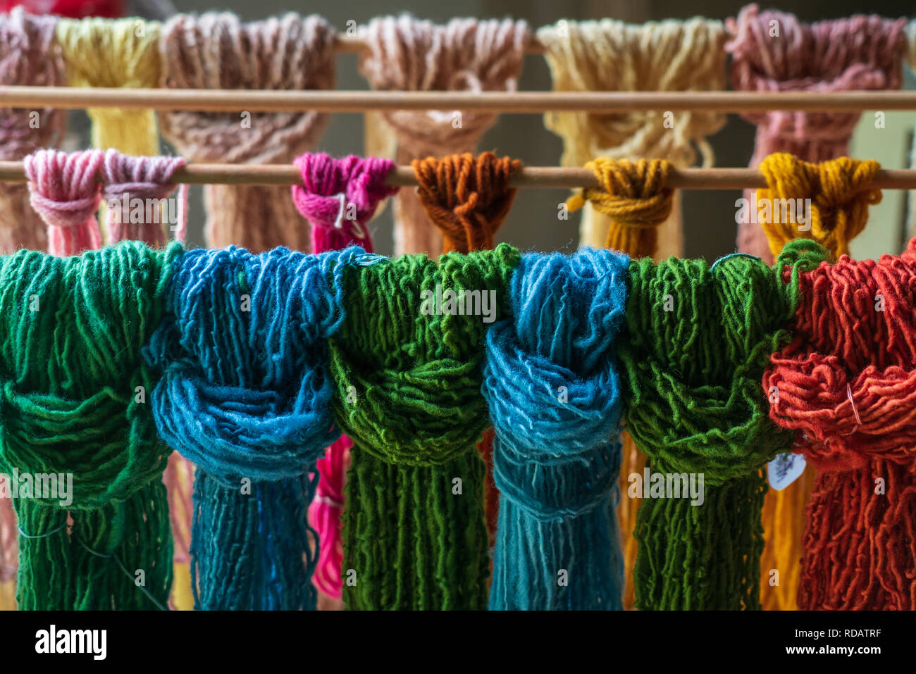 Colorful Yarn hanging from a dowl rod Stock Photo - Alamy