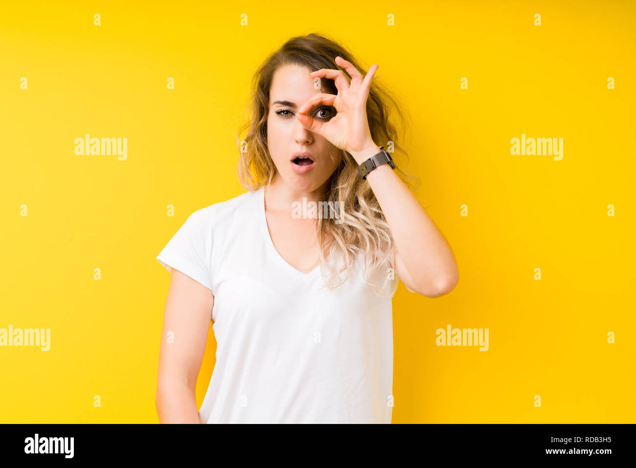 Young beautiful blonde woman over yellow background doing ok gesture ...