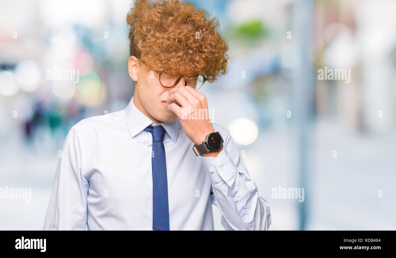 Young handsome business man with afro wearing glasses smelling ...