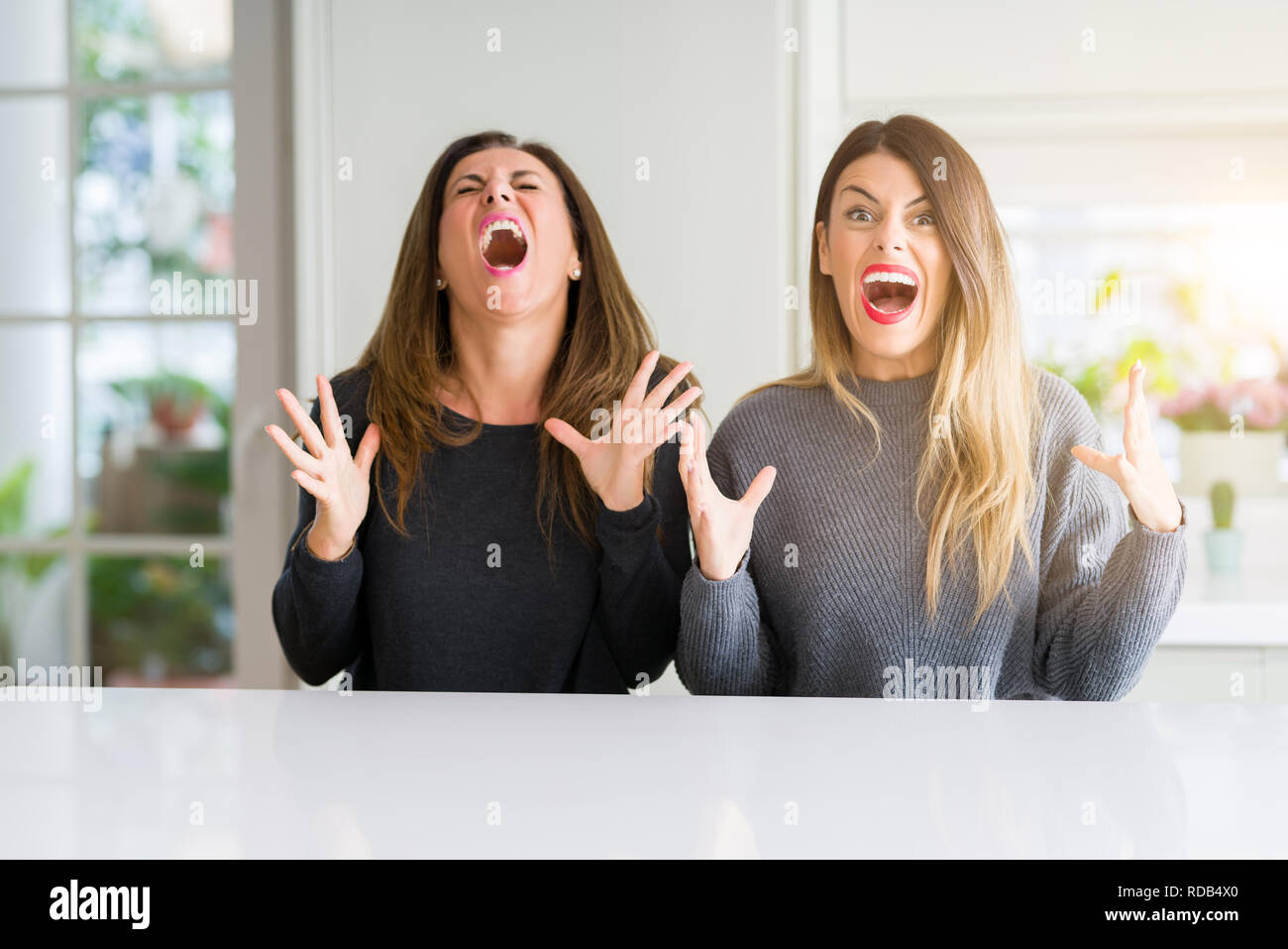 Beautiful family of mother and daughter together at home crazy and mad ...