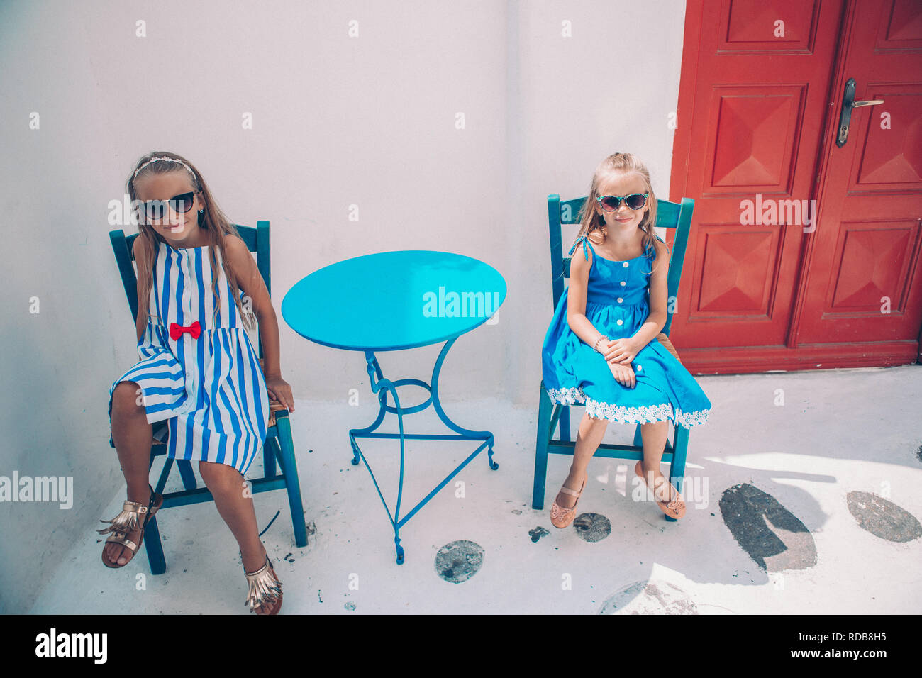 Two girls in blue dresses sitting on blue chairs Stock Photo - Alamy