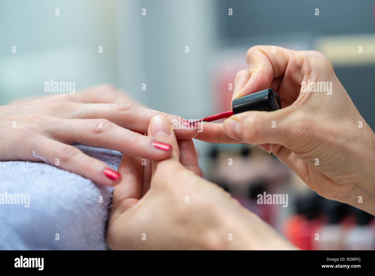 Closeup view of manicurist making manicure applying pink nail polish to ...