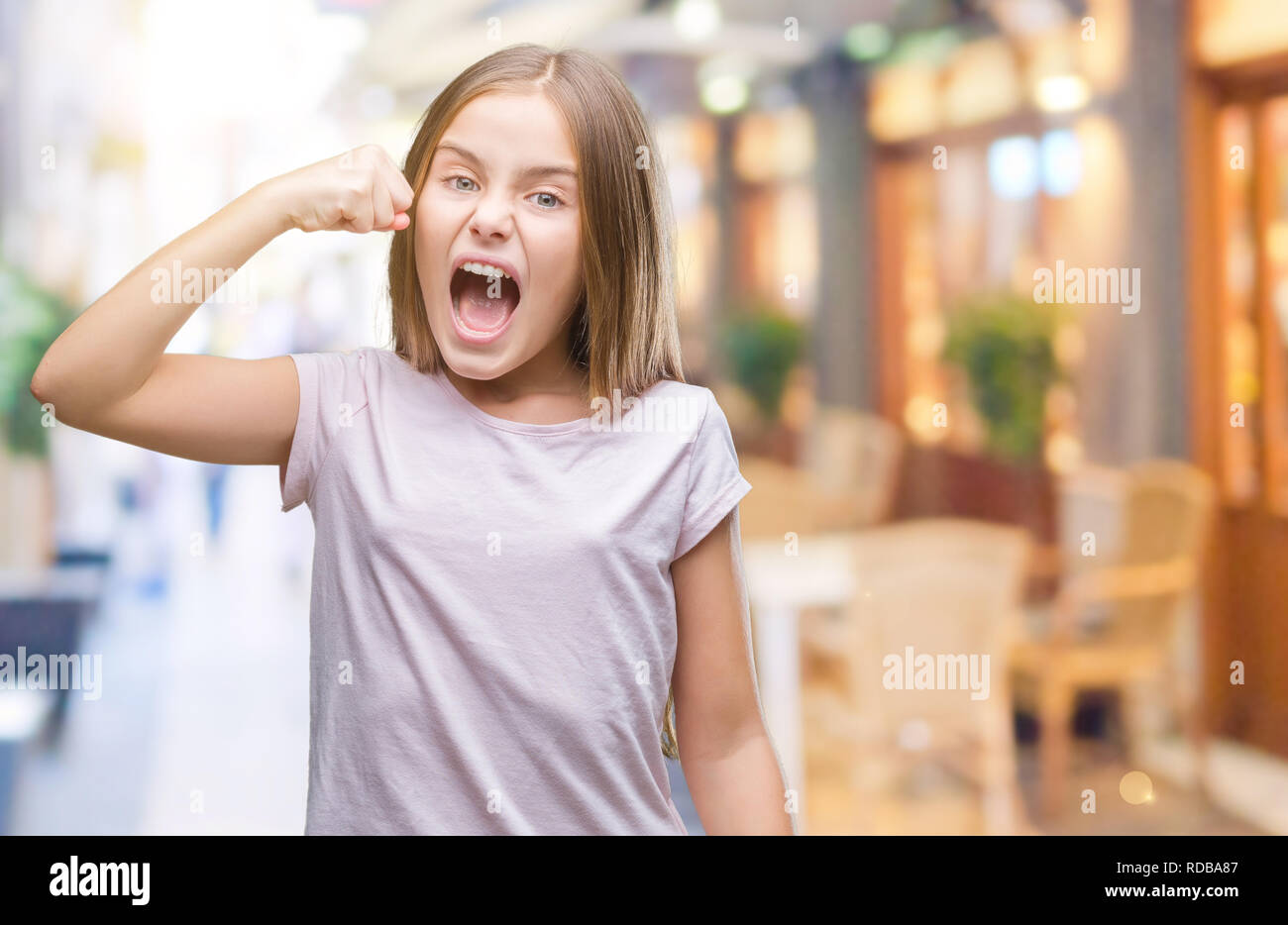 Young beautiful girl over isolated background angry and mad raising ...