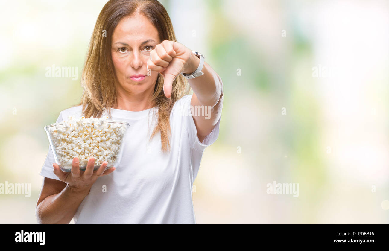 Middle age hispanic woman eating popcorn over isolated background with ...