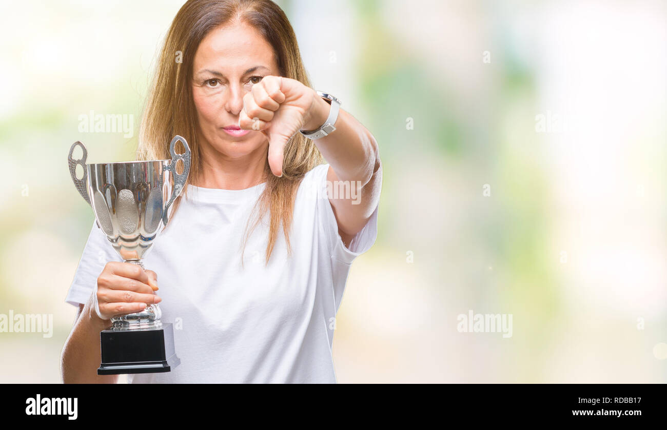 Middle age hispanic winner woman celebrating award holding trophy over ...
