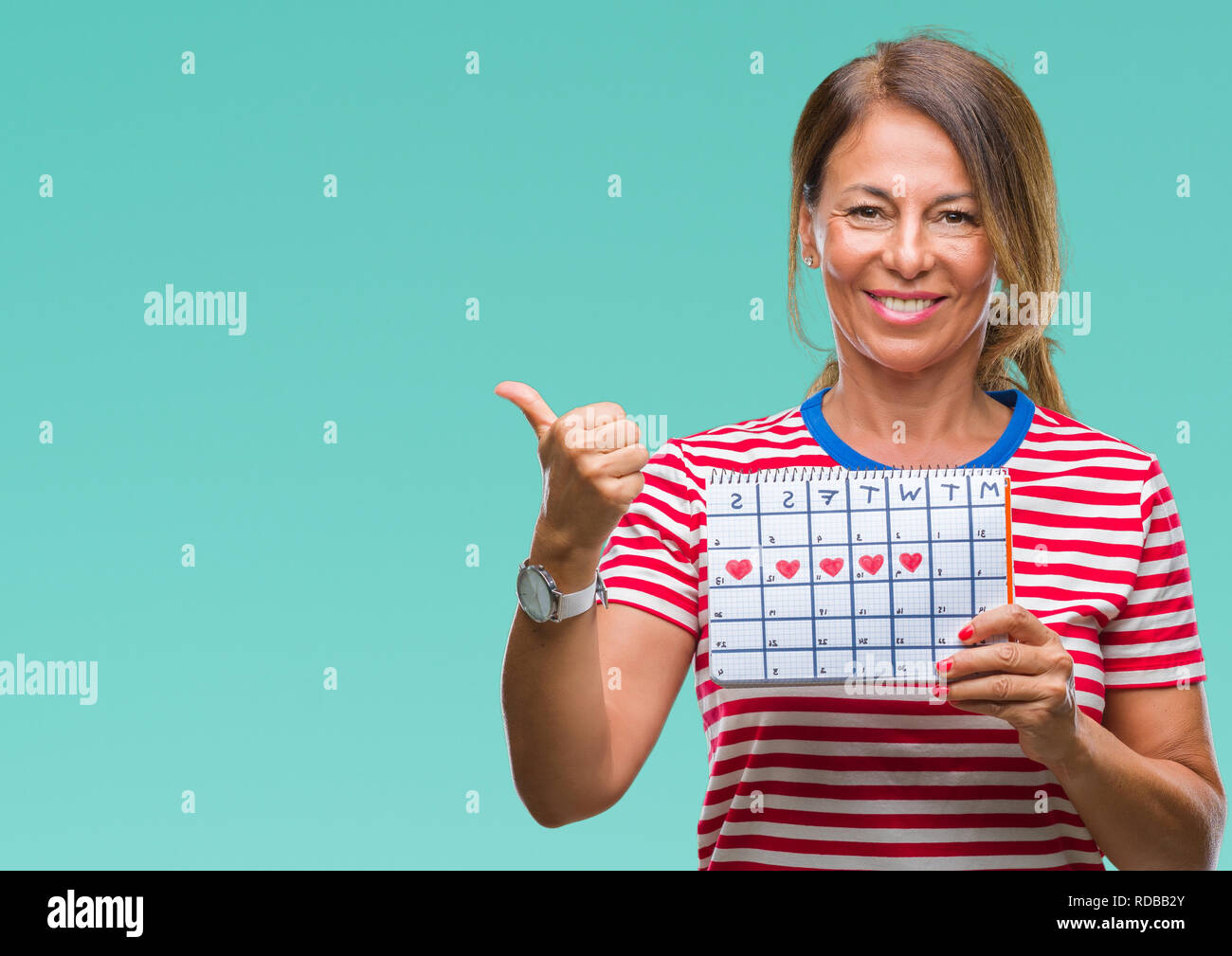 Middle age senior hispanic woman holding menstruation calendar over ...