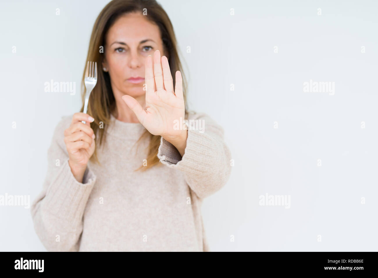 Middle age woman holding silver fork metal over isolated background ...