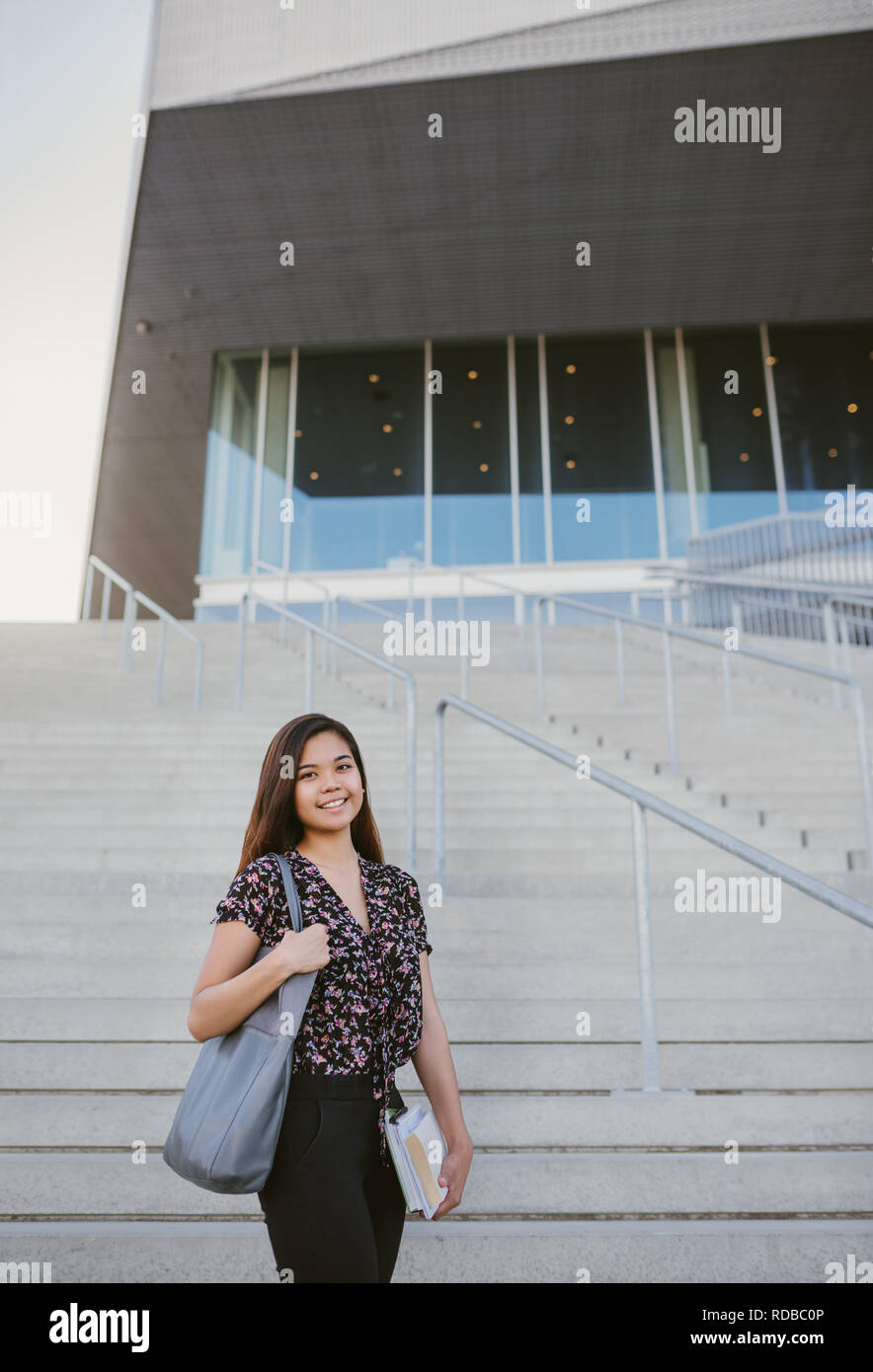 Smiling young Asian university student standing by campus stairs Stock ...