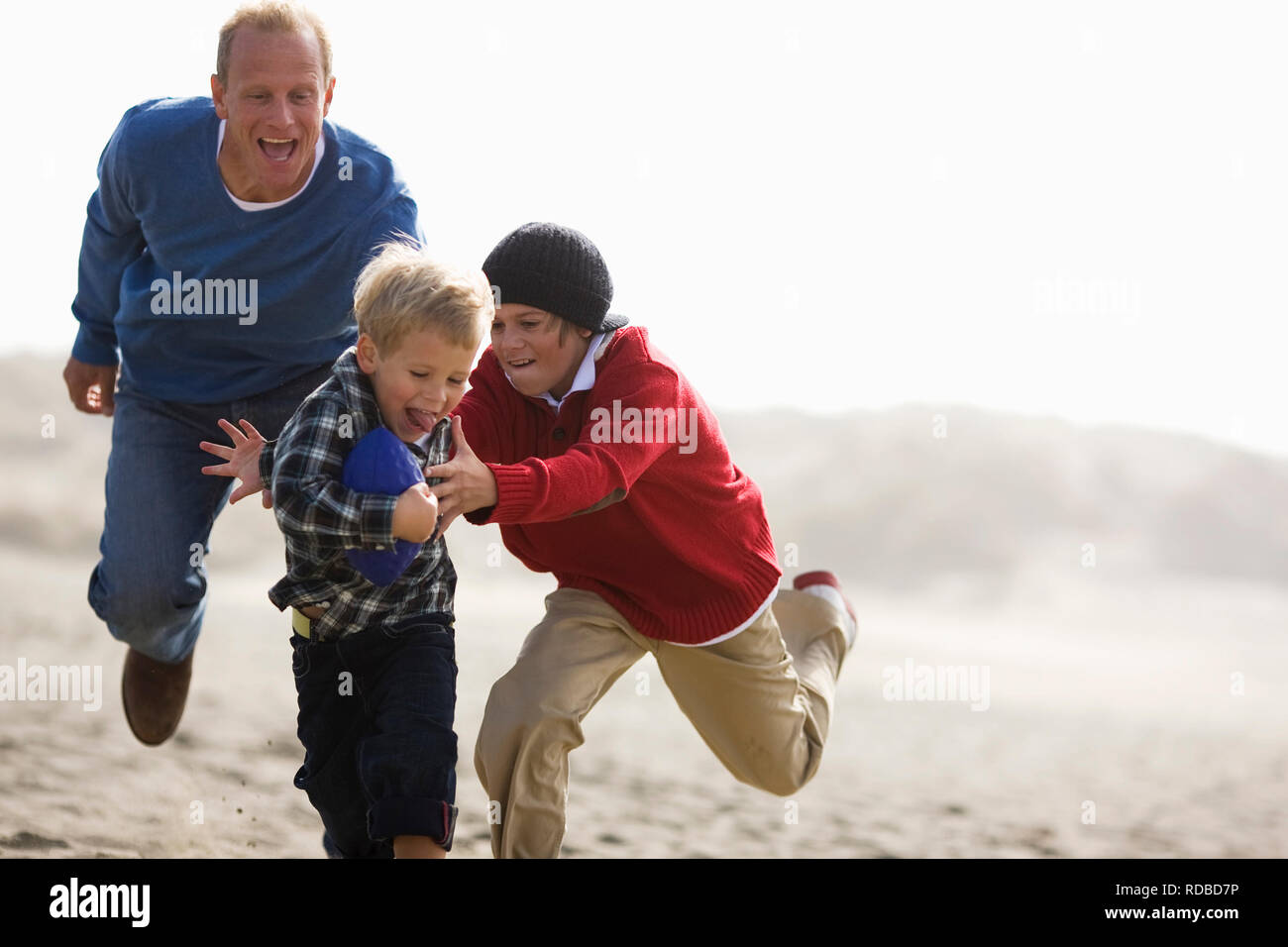 Young boy running with a ball while being chased by his brother an mid ...