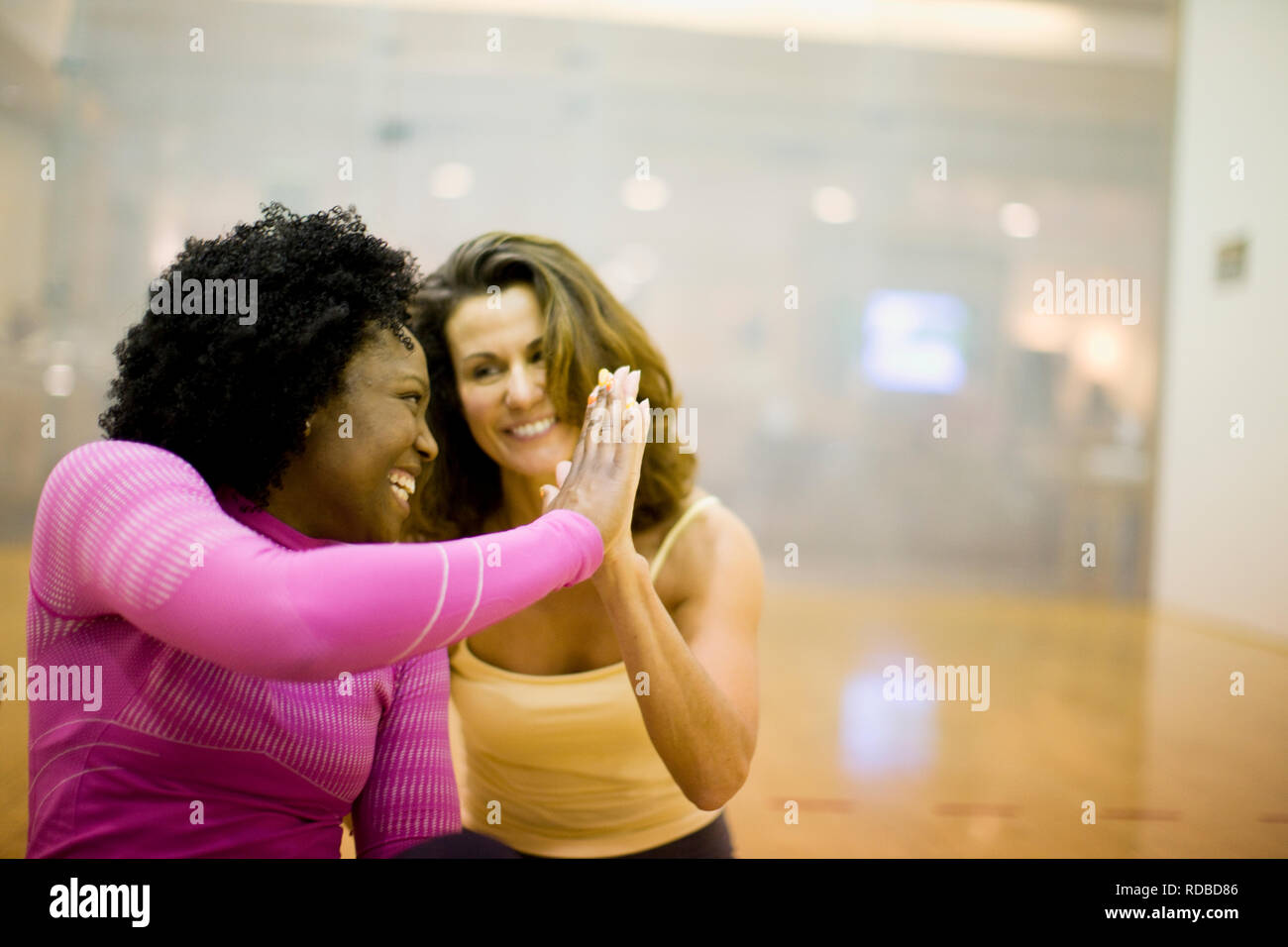 Two smiling woman giving each other a high-five inside a yoga studio ...