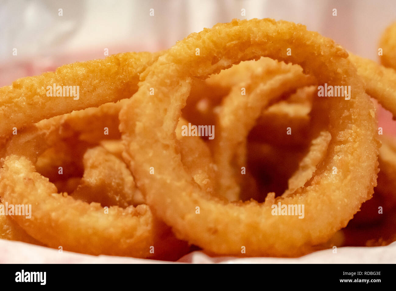 Close up view of deep friend golden onion rings in a basket with white ...