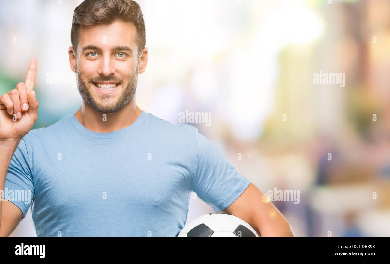 Young handsome man holding soccer football ball over isolated ...