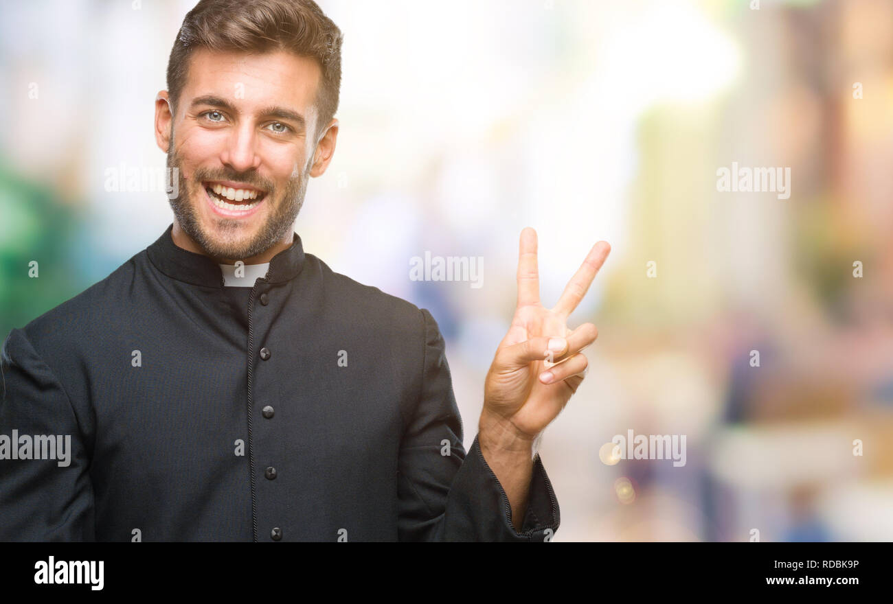 Young catholic christian priest man over isolated background smiling ...