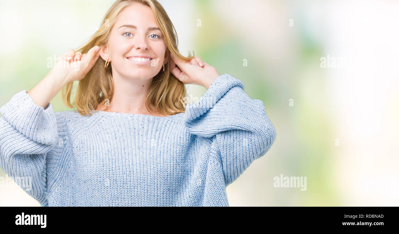 Beautiful young woman wearing blue sweater over isolated background ...