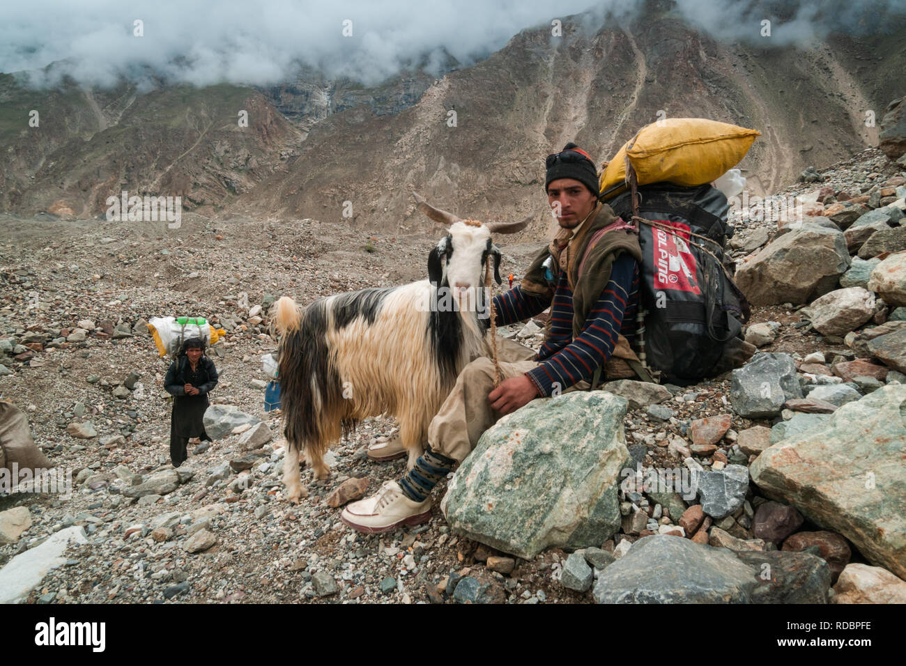 Karakoram, Pakistan - July 24, 2018: Sherpa with a goat having a rest ...