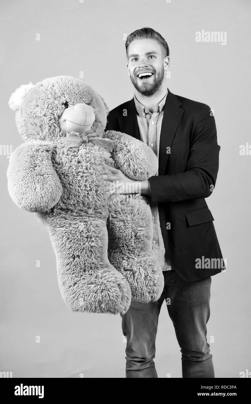 Happy man hold grey teddy bear. Macho smile with big animal toy. Thisi ...