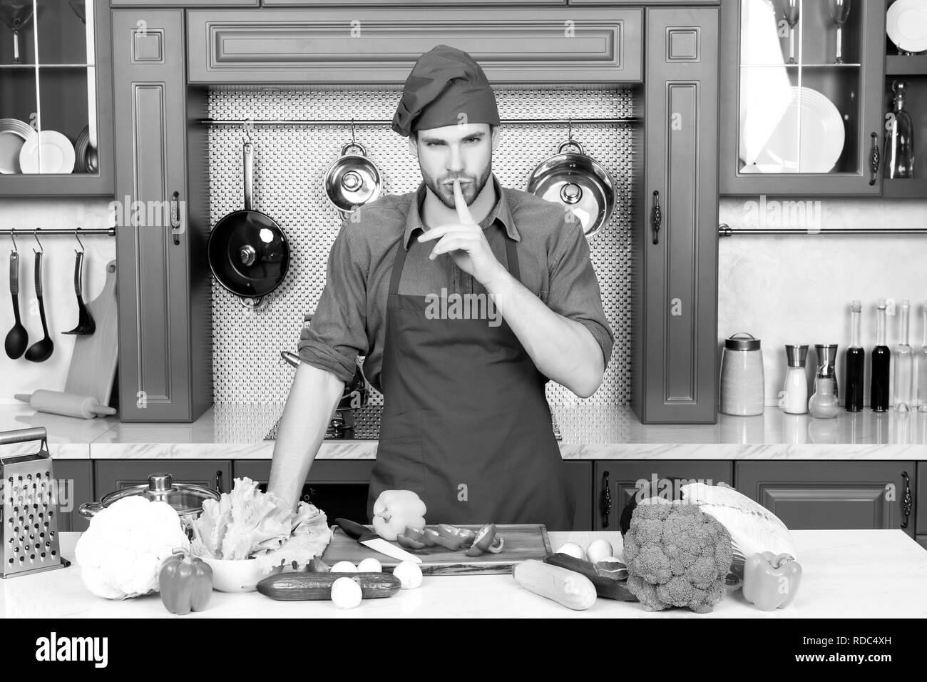 Man cook secret dish in kitchen. Chef with silence gesture finger at ...