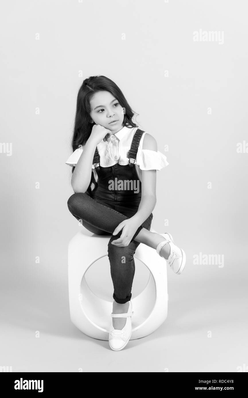 Child with thinking face sit on chair on blue background. Preteen model ...