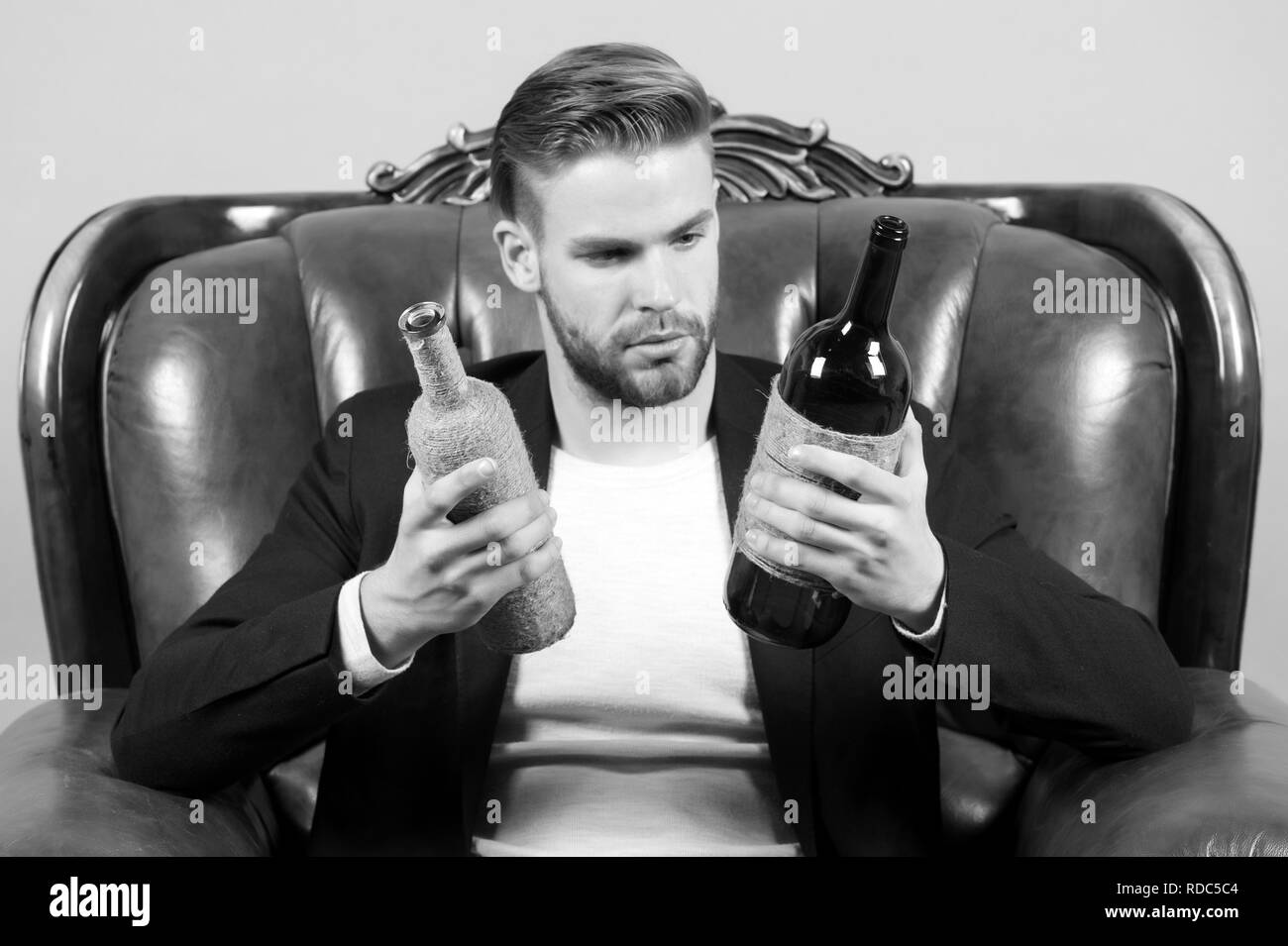 Guy choose wine to drink, choice. Man with wine bottles sit in brown ...