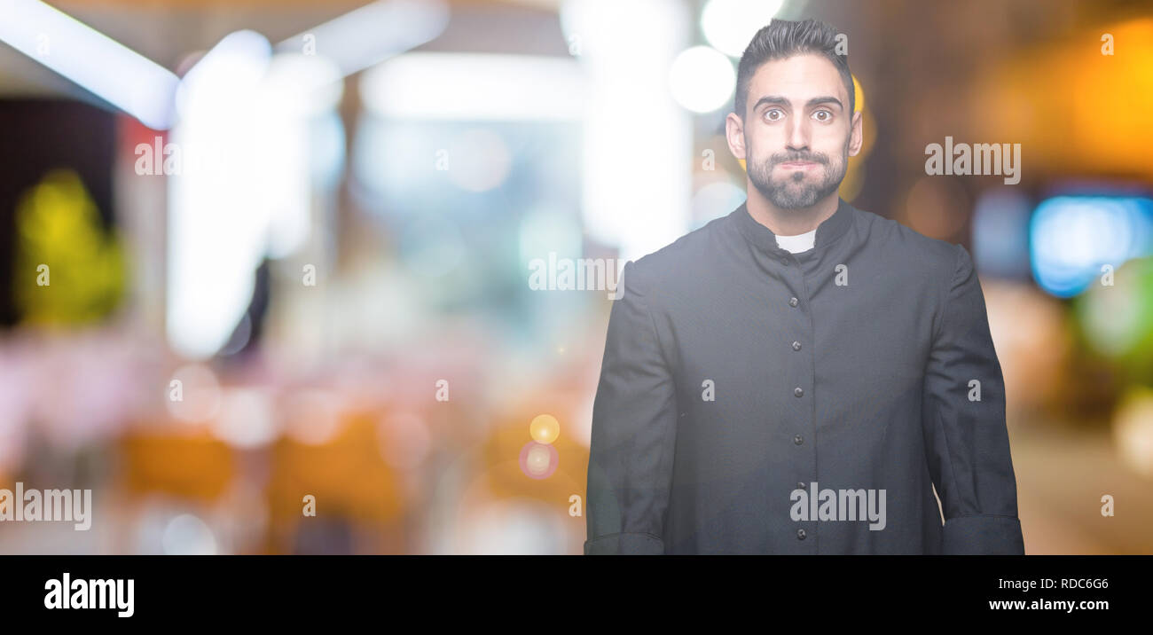 Young Christian priest over isolated background puffing cheeks with ...