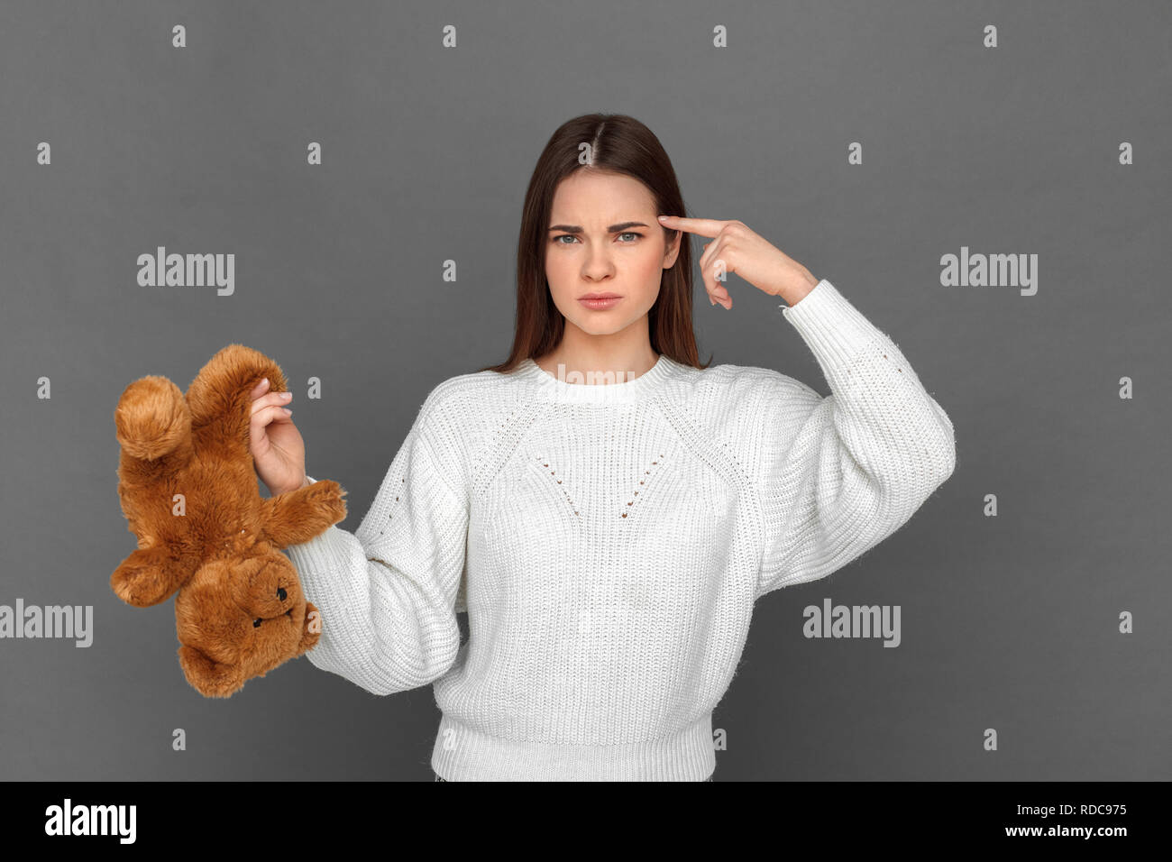 Freestyle. Young girl standing isolated on grey with teddy bear ...