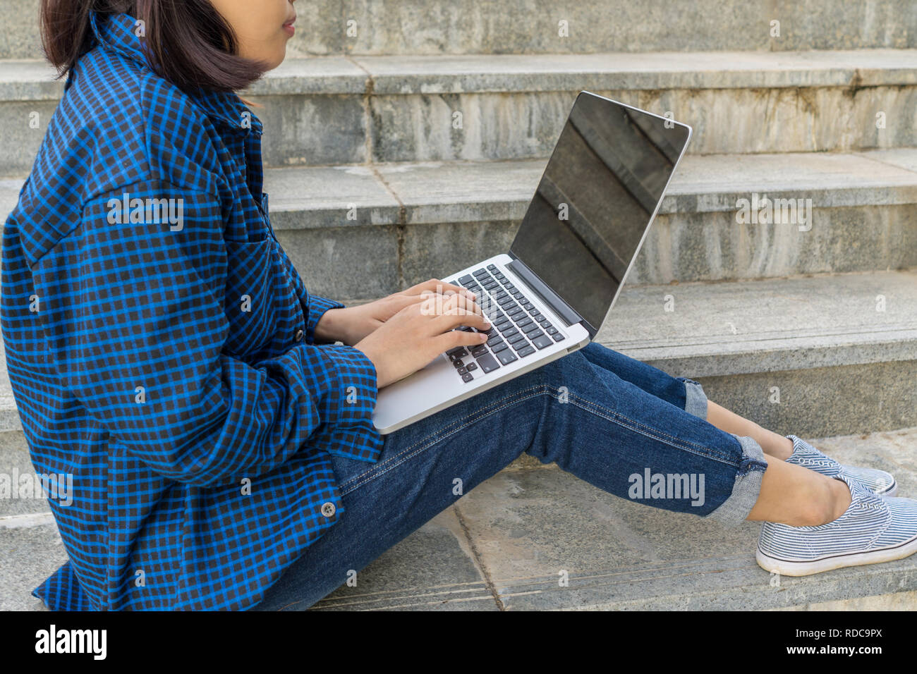 Female student sitting on campus stair, working on laptop Stock Photo ...