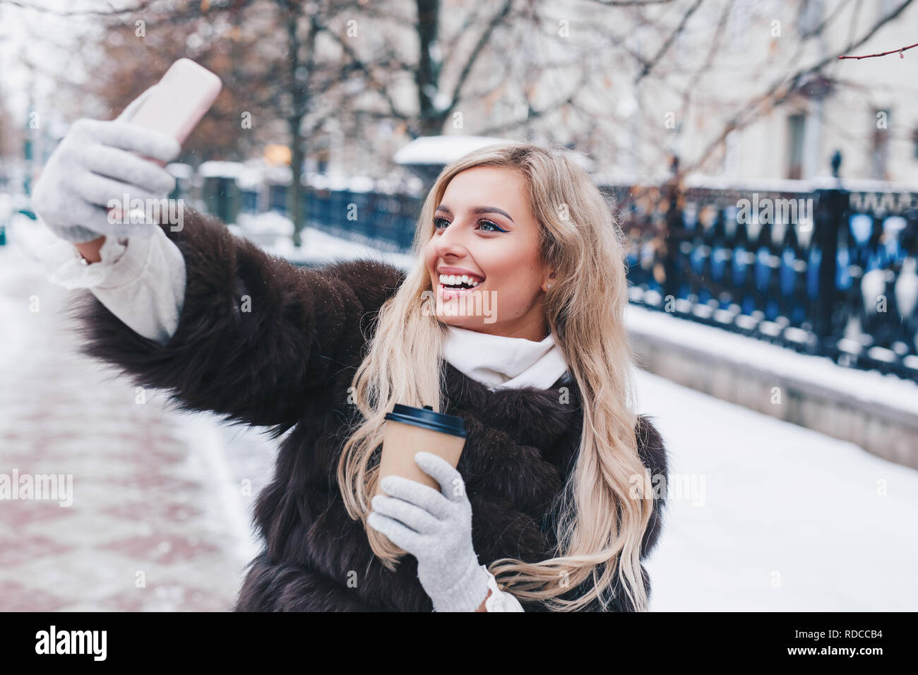 Beautiful girl takes funny winter selfie on city street Stock Photo - Alamy