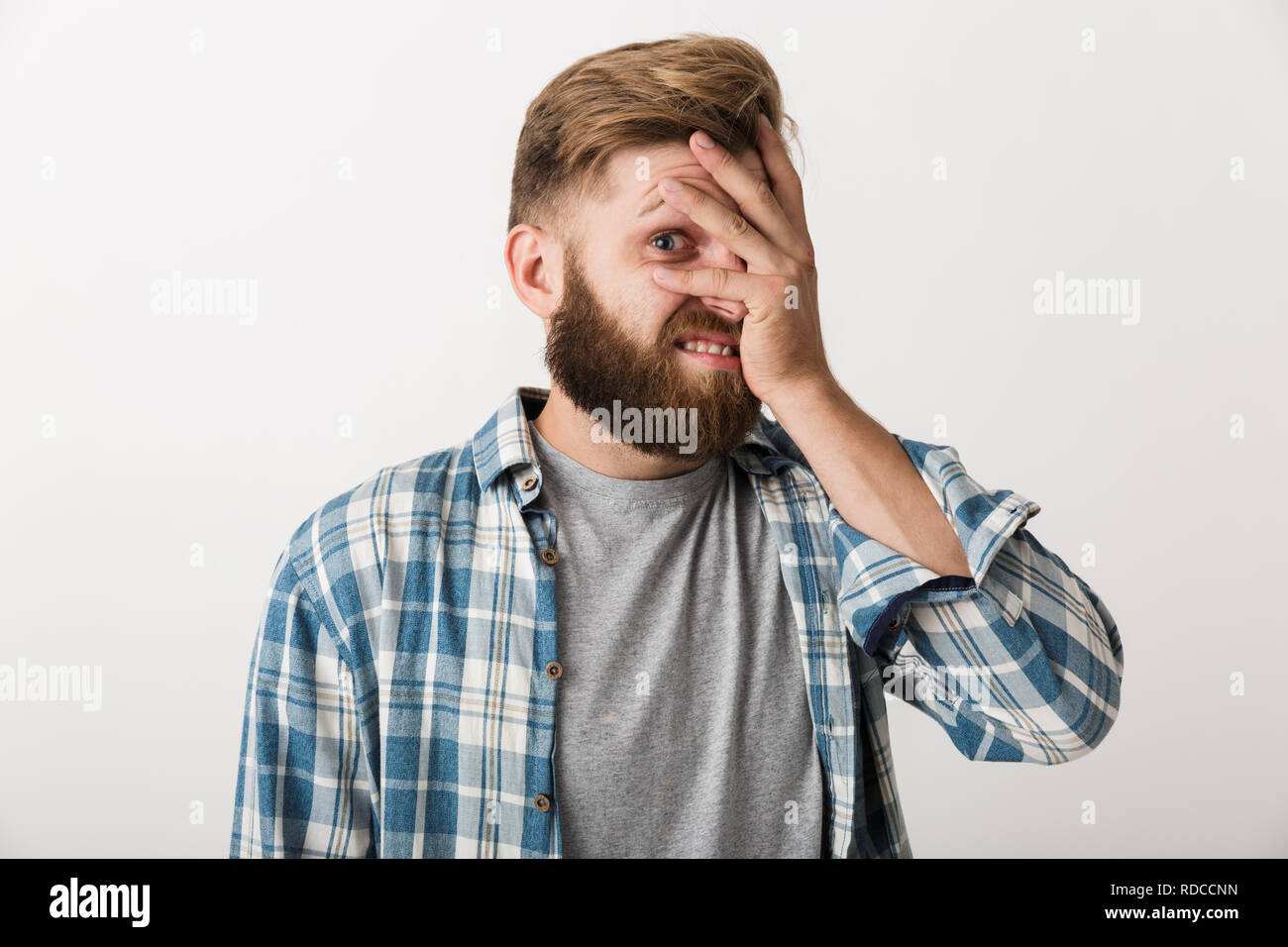 Ashamed bearded man dressed in plaid shirt standing isolated over white ...
