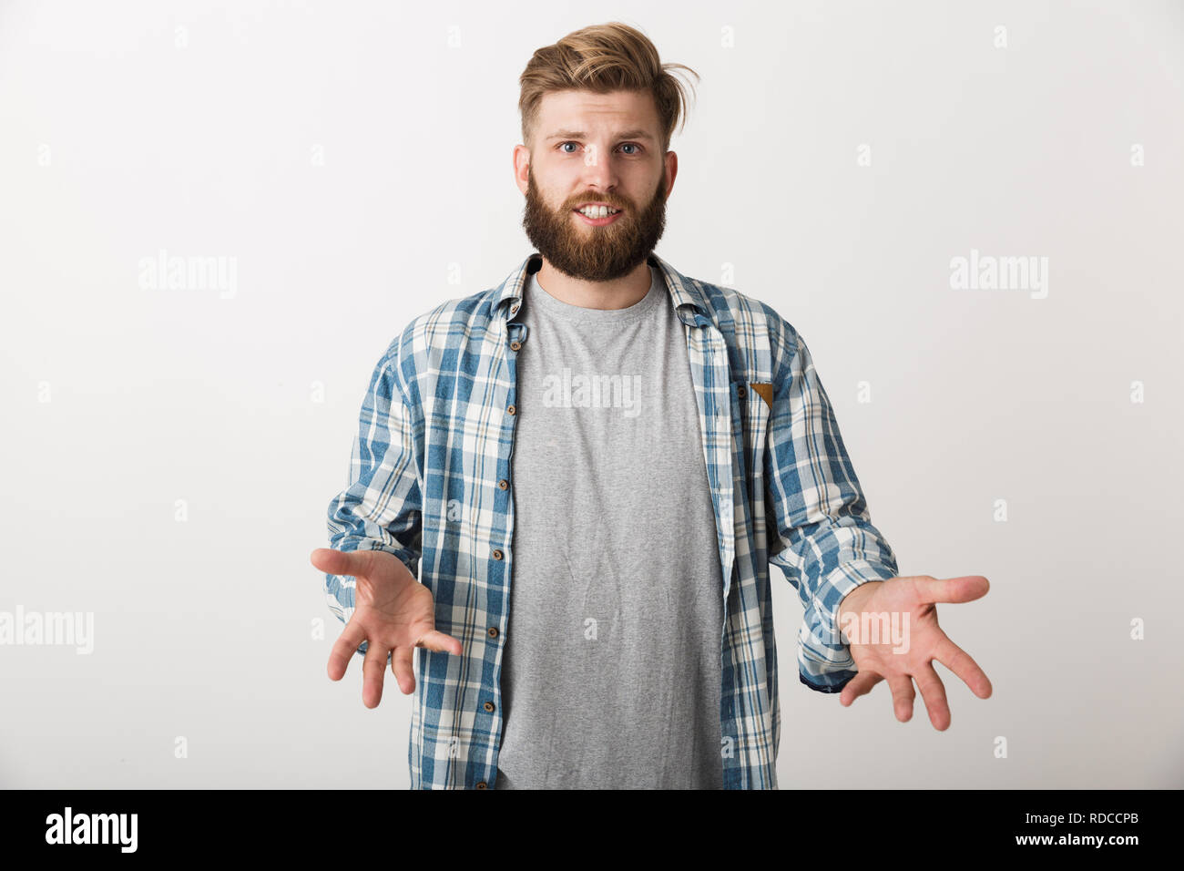 Confused young man dressed in plaid shirt standing isolated over white ...