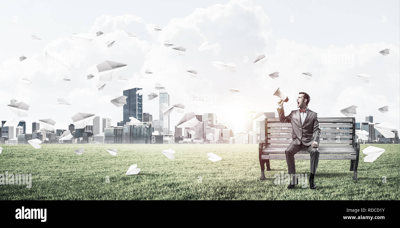 Young businessman sitting on bench and screaming emotionally in ...