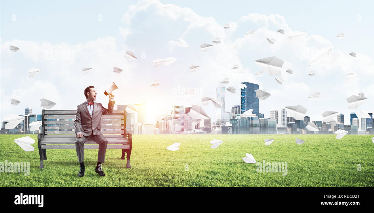 Young businessman sitting on bench and screaming emotionally in ...
