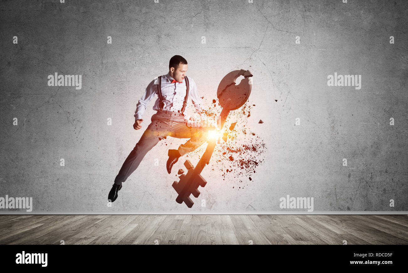 Determined businessman jumping and breaking with kick stone key figure ...