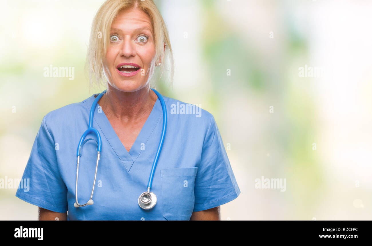 Middle age blonde nurse surgeon doctor woman over isolated background ...