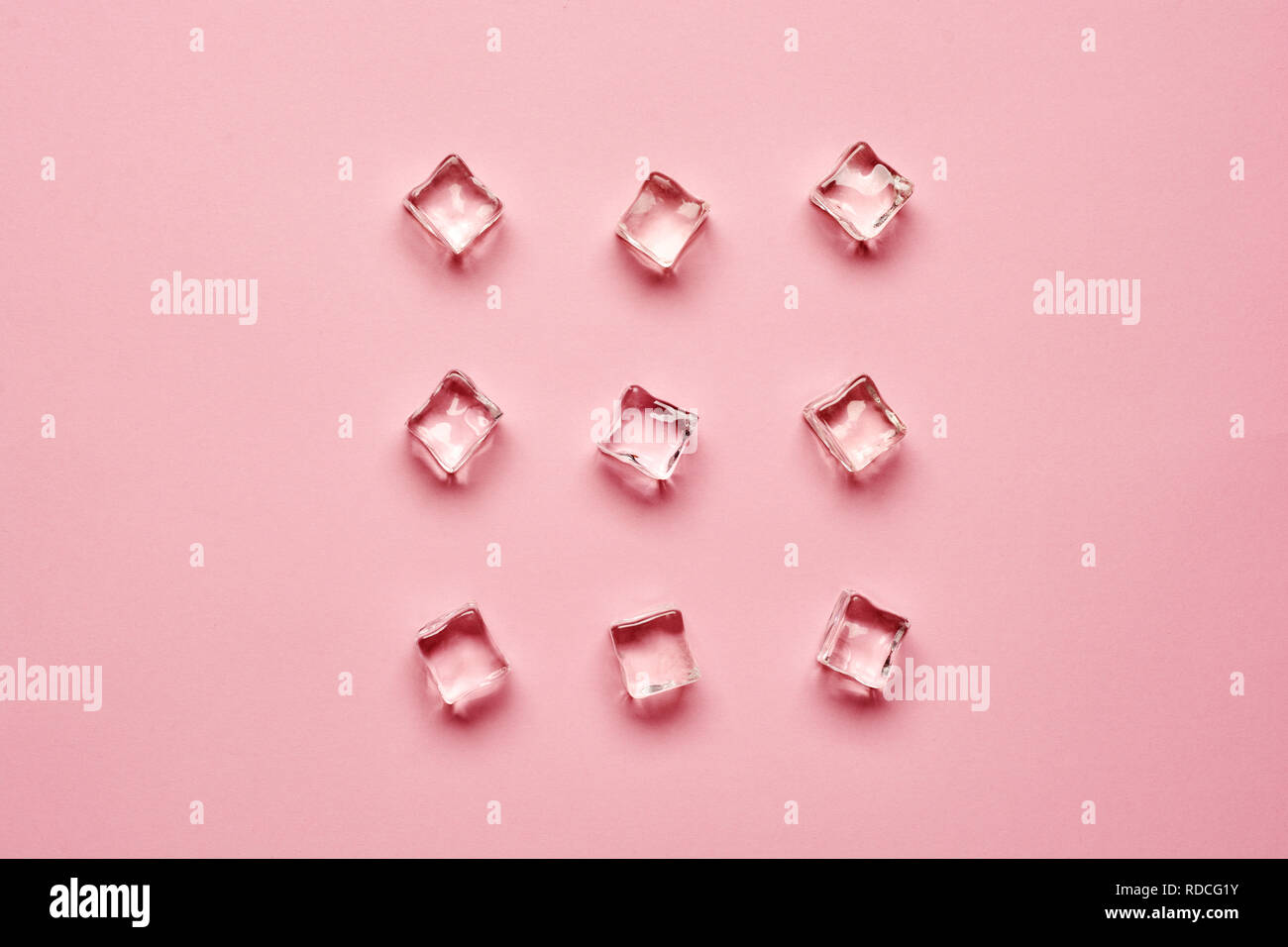 Set pieces of pure ice cubes on pink background with copy space. Top ...