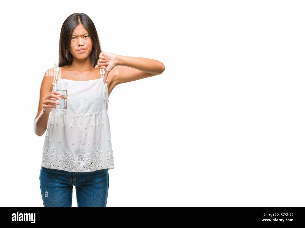 Young asian woman drinking glass of water over isolated background with ...