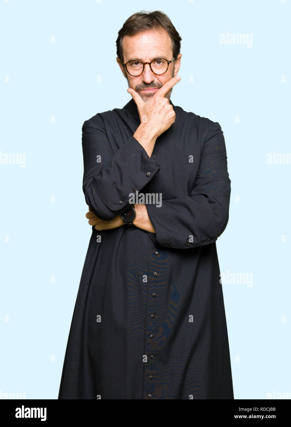 Middle age priest man wearing catholic robe looking confident at the ...