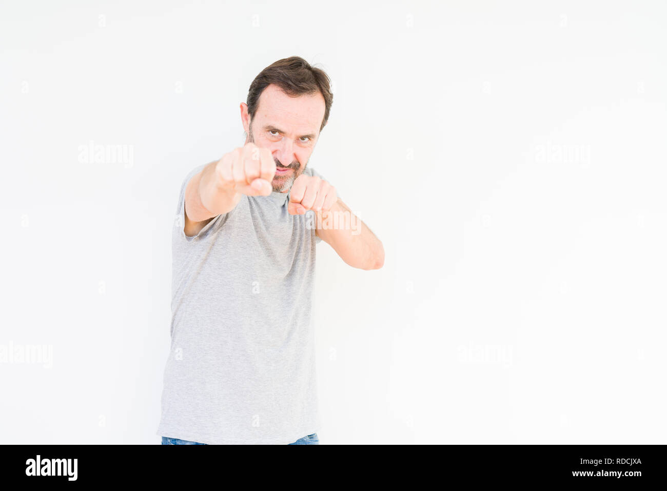 Handsome senior man over isolated background Punching fist to fight ...