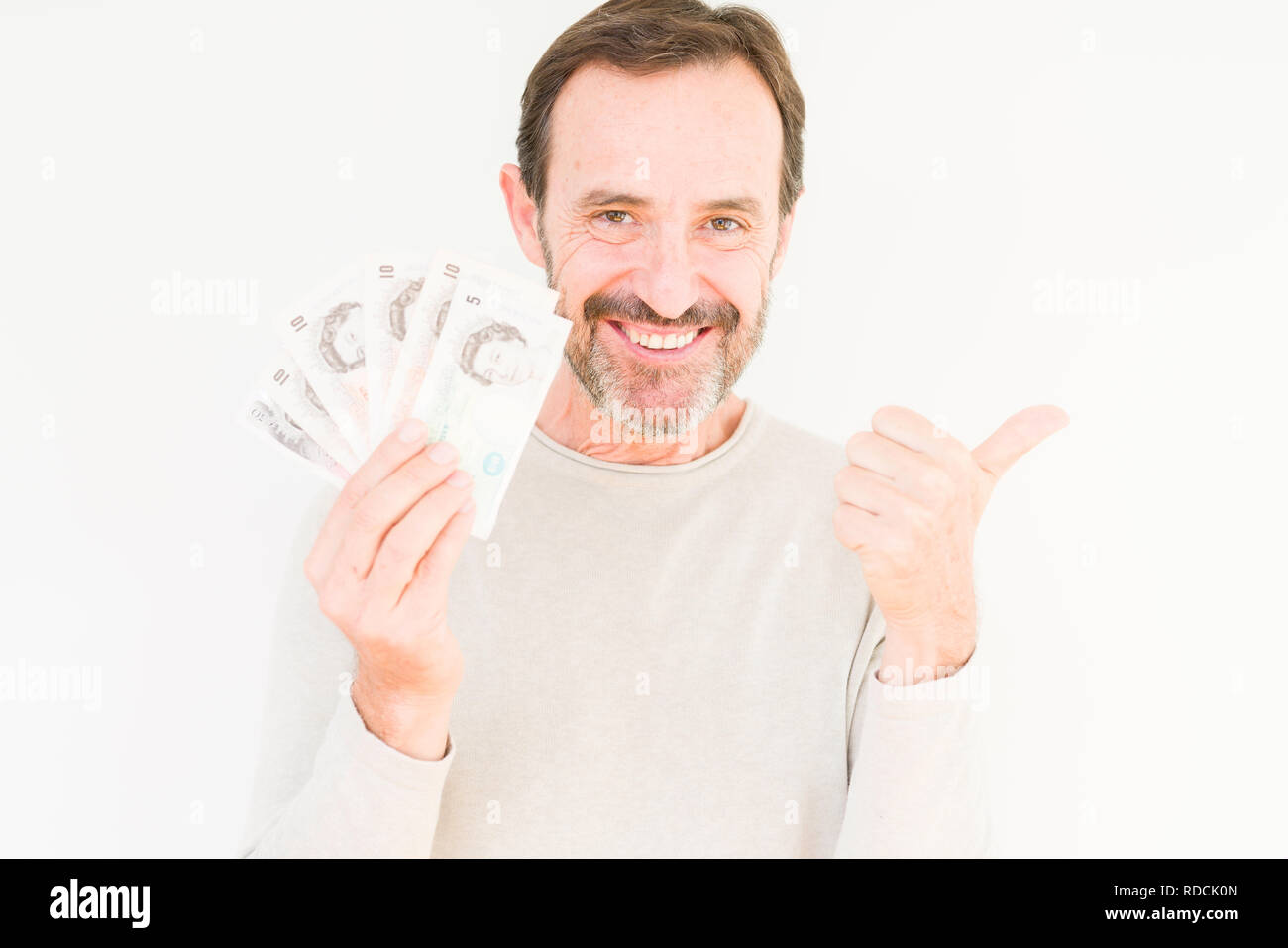 Senior man holding bunch of pounds bank note over isolated background ...