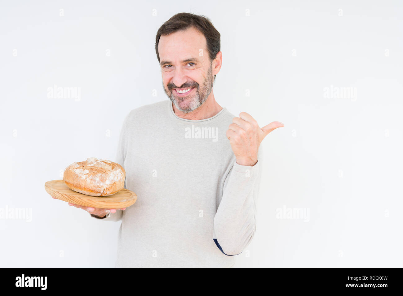 Senior man holding homemade fresh bread over isolated background ...