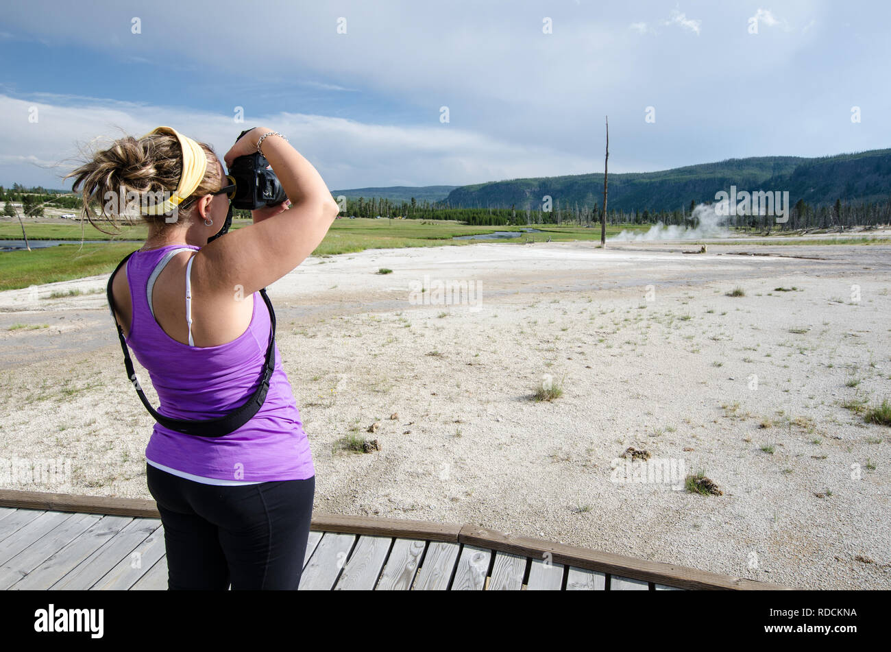 Female tourist at Yellowstone National Park uses a DSLR camera to ...