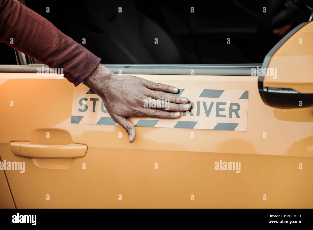 African-American driving instructor showing his student orange car ...