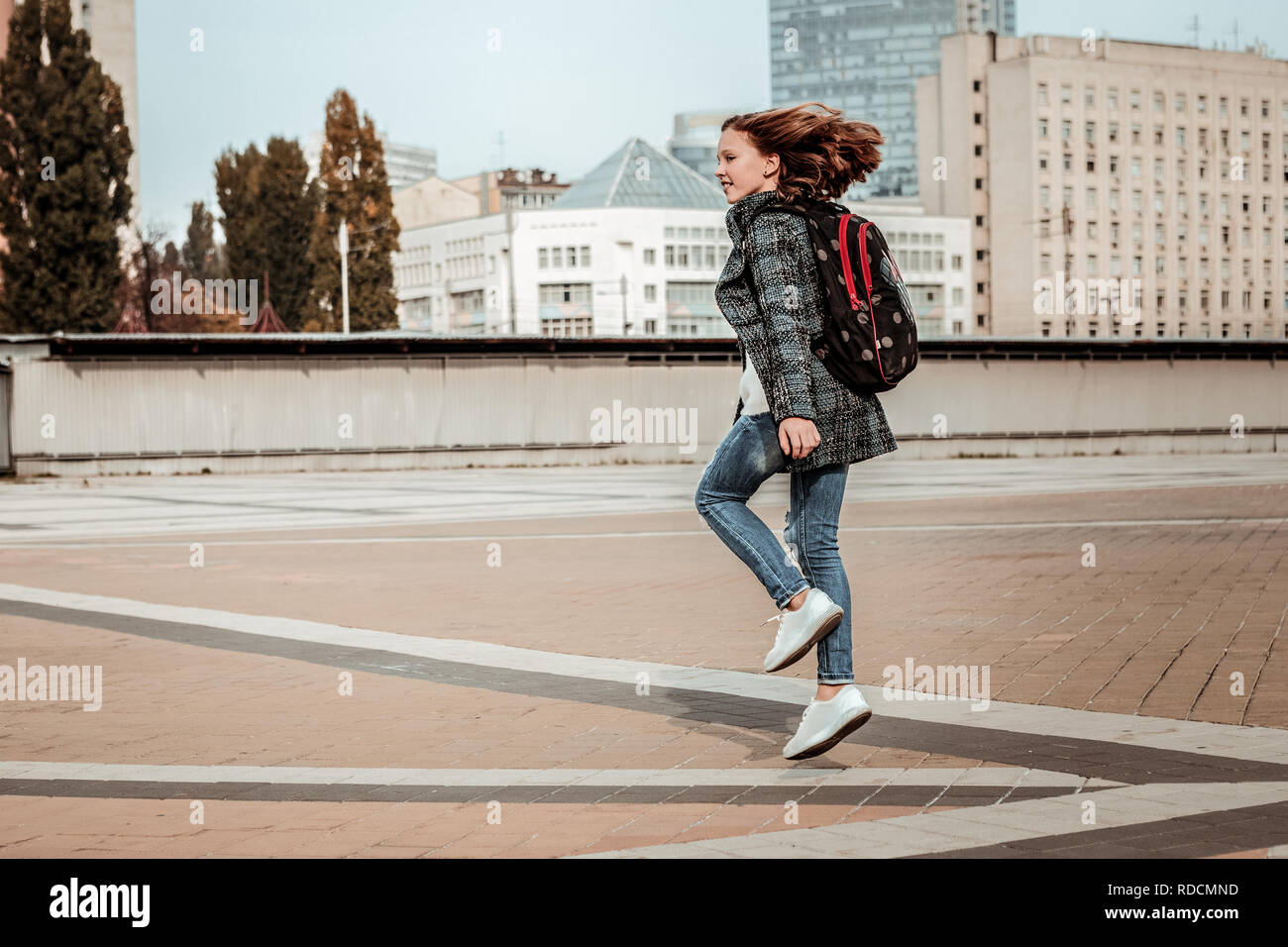 Girl happily skipping through the city center Stock Photo - Alamy