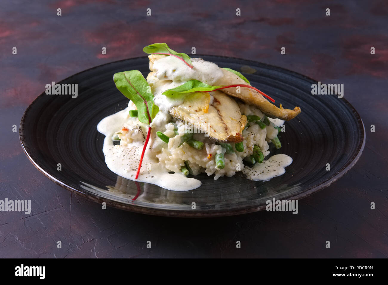 Fried fillet of white fish with rice and green beans decorated with ...