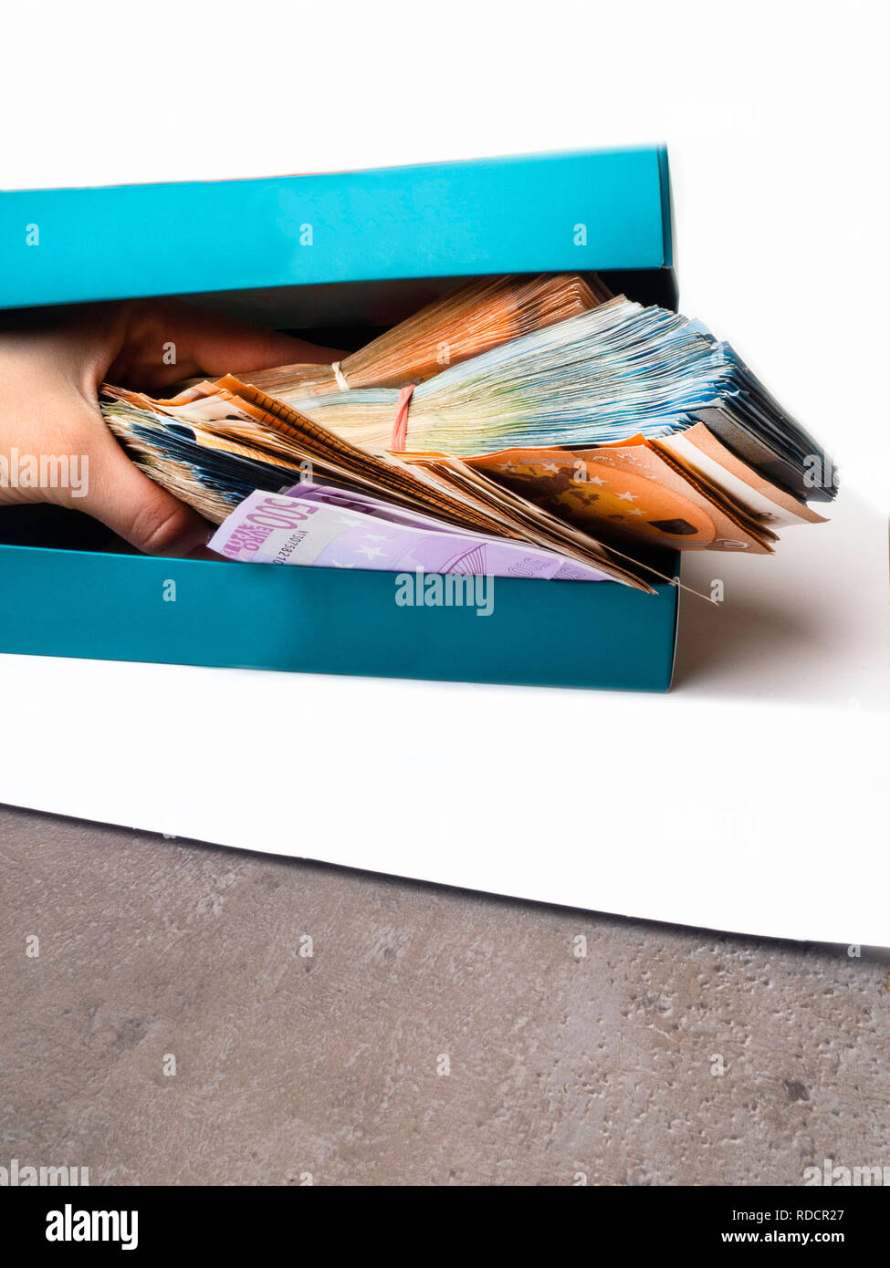 Different euro cash money banknotes in hand in blue box Stock Photo - Alamy