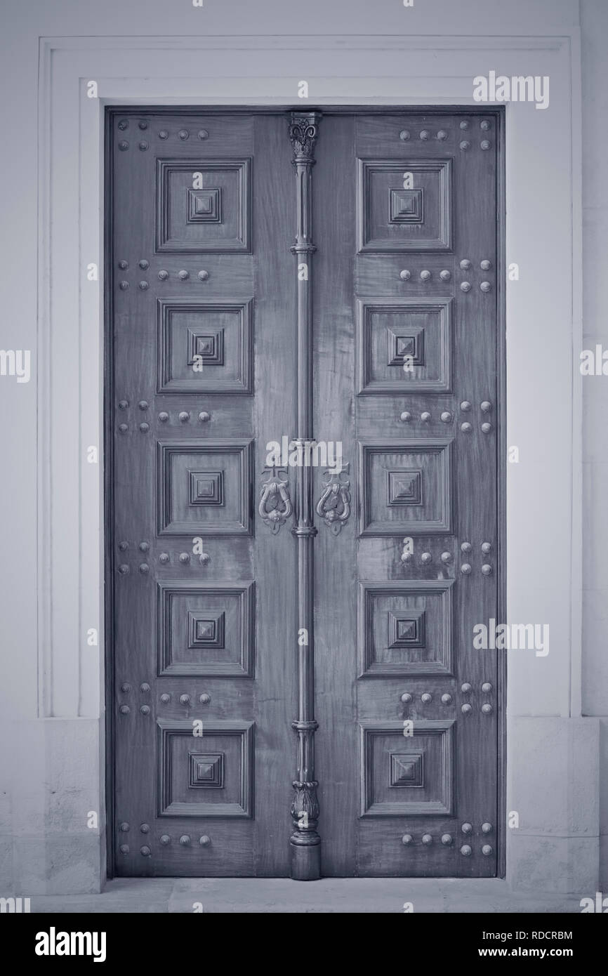 Wooden old catholic church door. Converted black and white. Toned blue ...