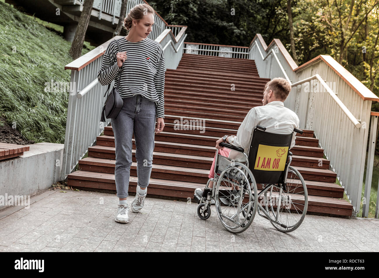 Serious young girl looking at invalid man Stock Photo - Alamy